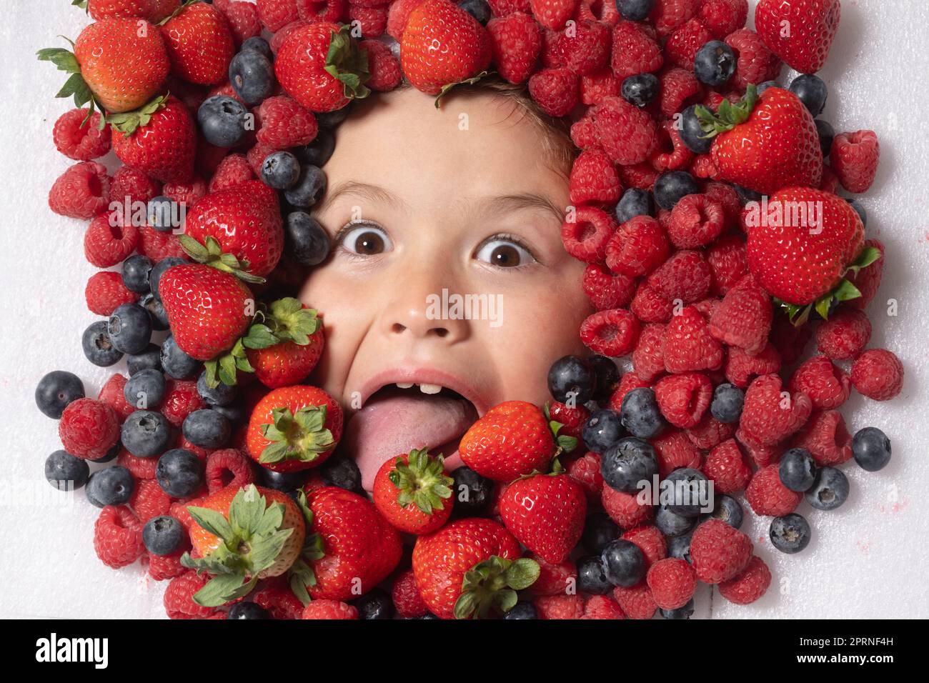 Kids face with close-up berry. Berries mix of strawberry, blueberry ...