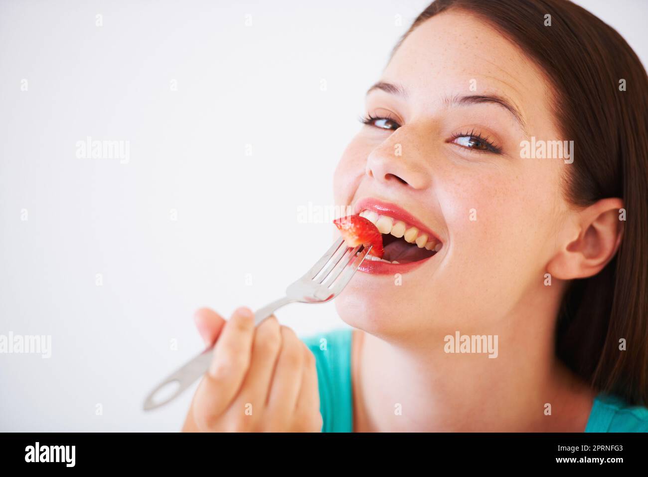 Enjoying some fresh fruit. Portrait of an attractive young woman eating ...