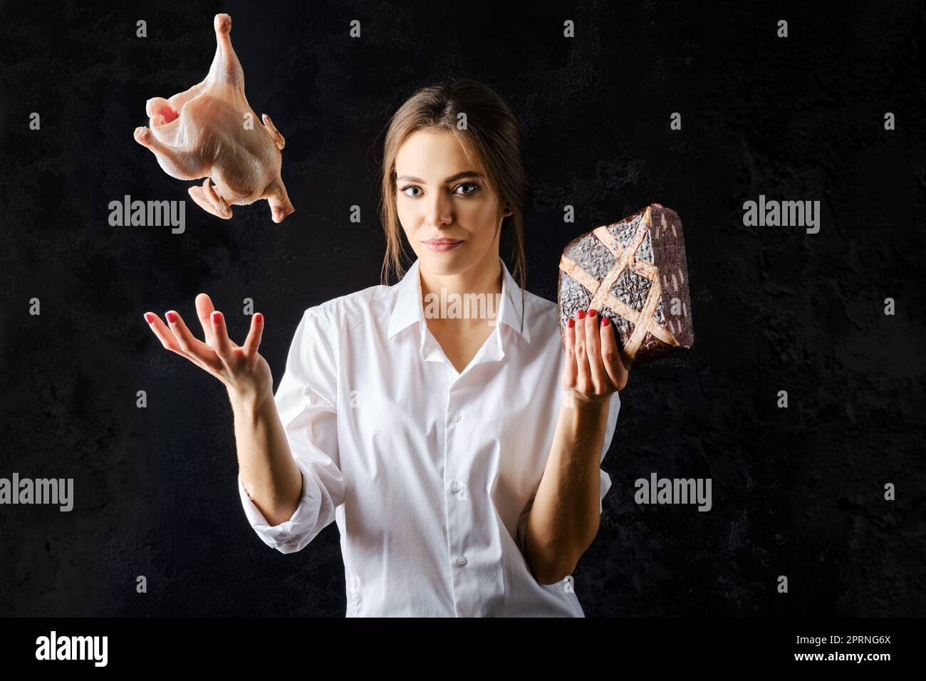 Young woman tossing up fresg chicken with one hand and holding meat pie ...