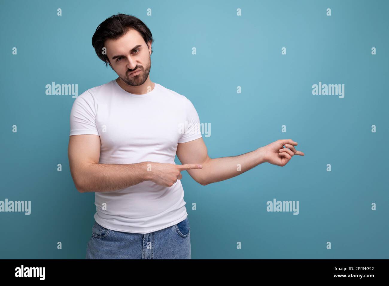 lazy tired brunette man in a white t-shirt and jeans points a finger ...