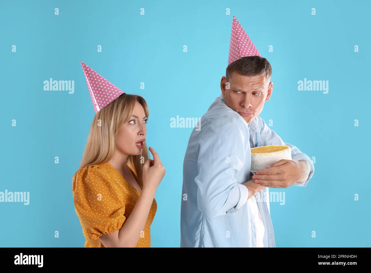 Greedy man hiding birthday cake from woman on turquoise background ...