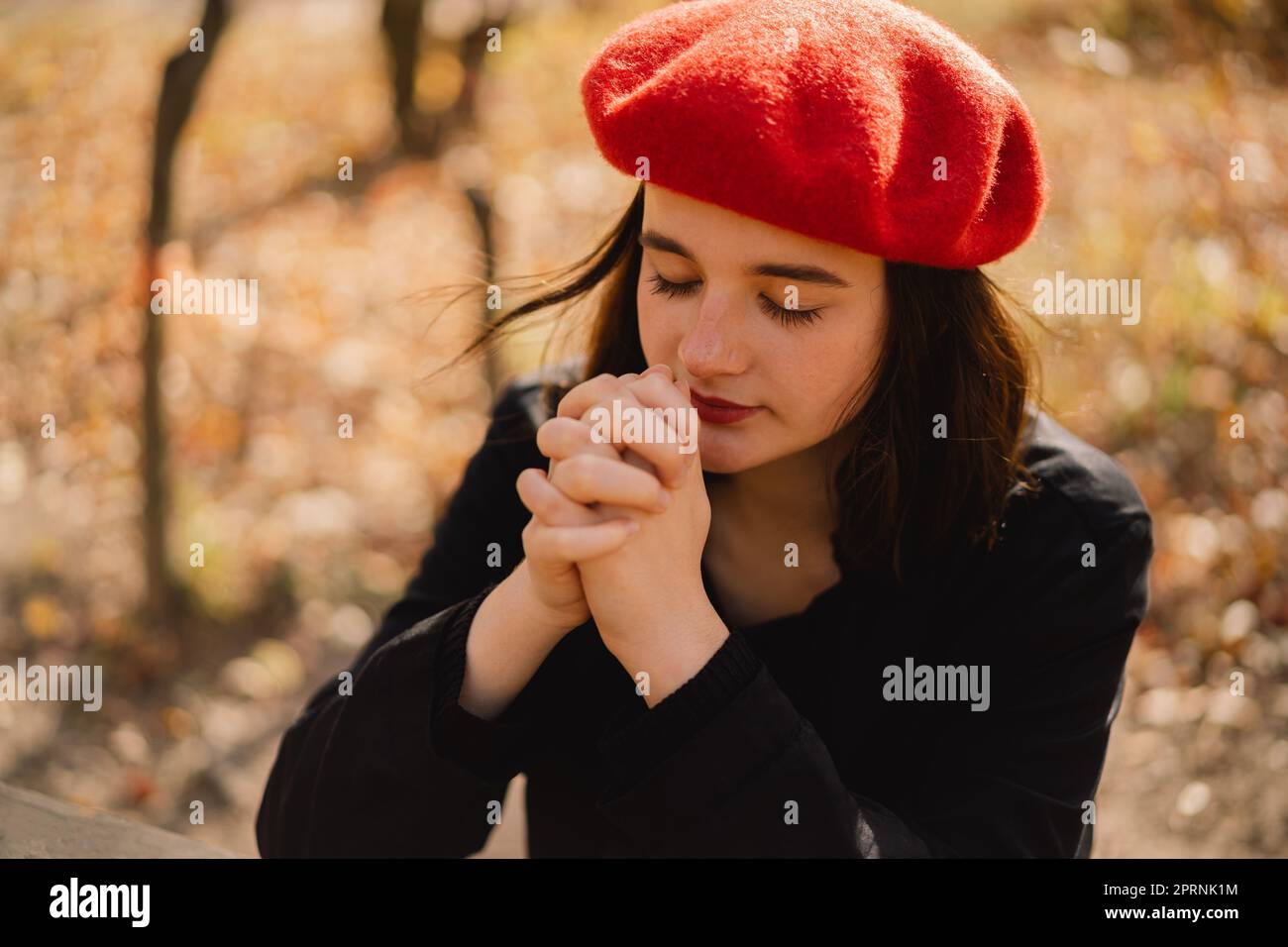 Teen girl closed her eyes and praying. Hands folded in prayer concept ...