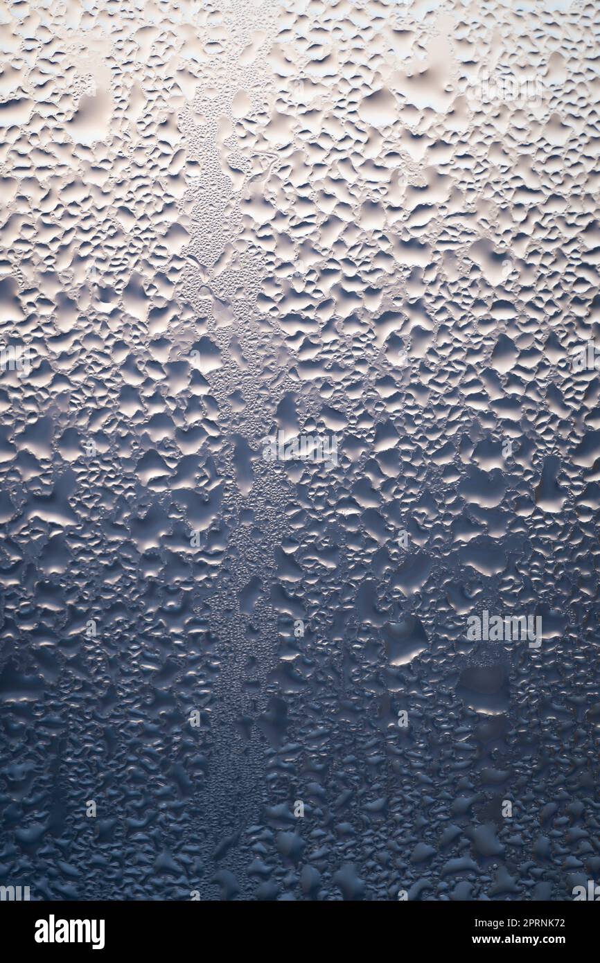 backlit chaotic water drops on lightbeige and blue glass background ...