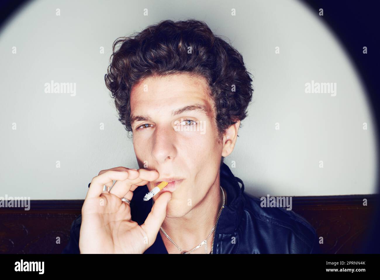 Taking a drag. Portrait of a young man inhaling deeply on a cigarette ...