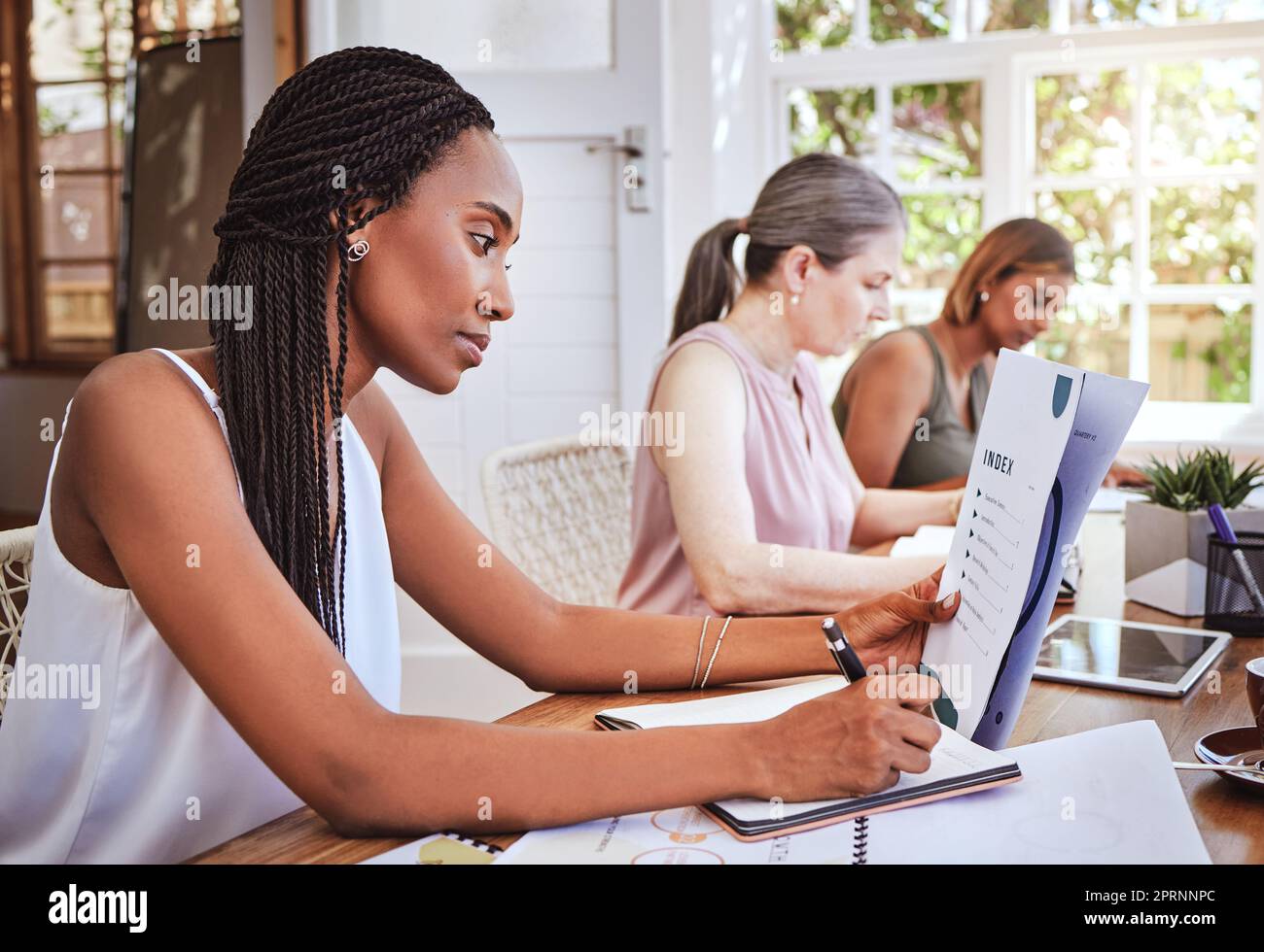 Black woman with business documents, writing at desk and women working ...