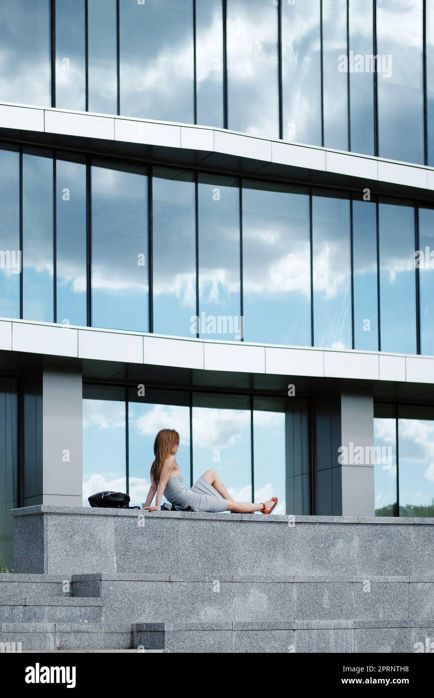 Pretty girl sitting on marble surface with bent knee. Reflection of the ...