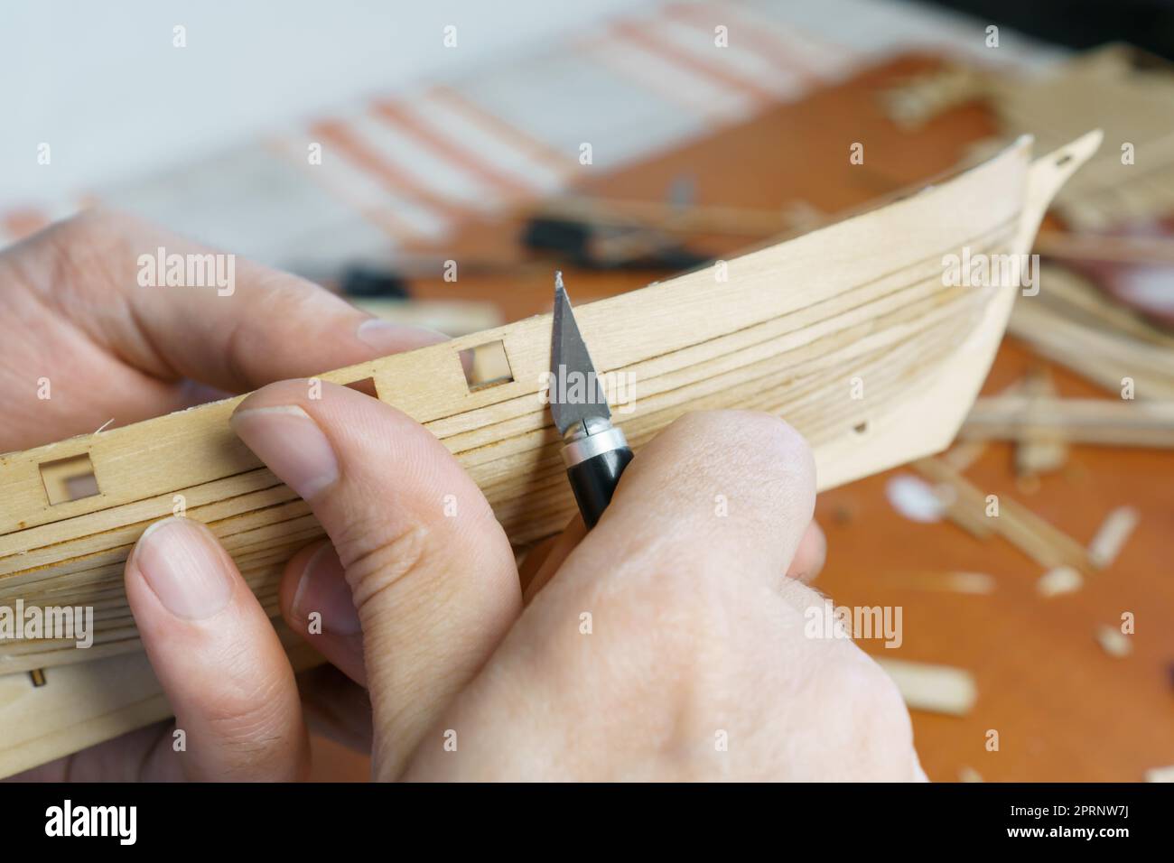 Hands of man cutting out details for ship model with clerical knife ...