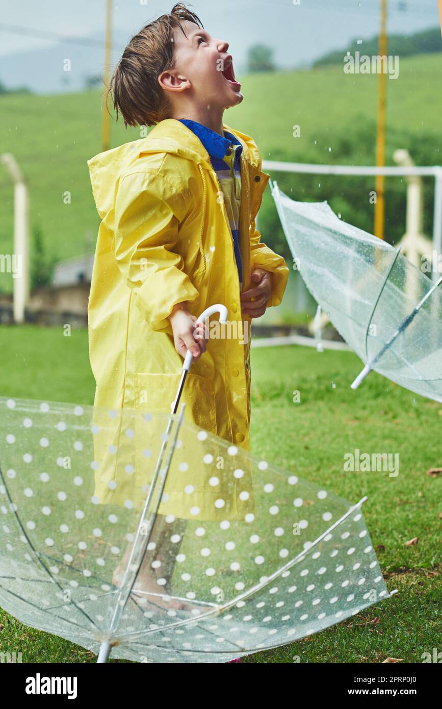 Having a drink from the rain. a cheerful little boy standing with an ...