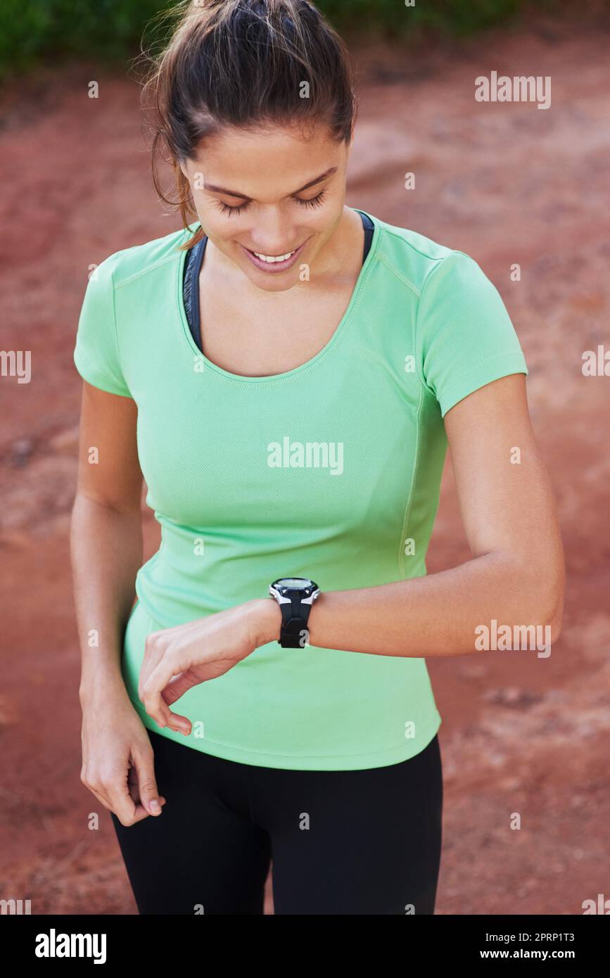 I beat my best. a young woman checking her watch while out running ...