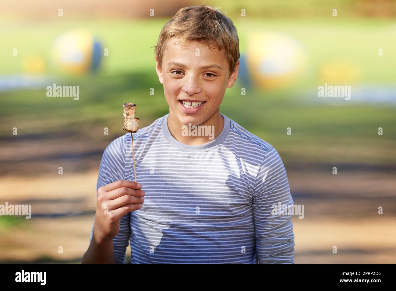 Mmm melted marshmallows. Portrait of a young boy holding a roasted ...