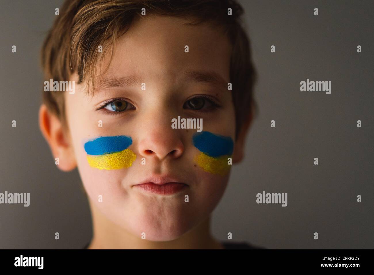 Portrait of a Ukrainian boy with a face painted with the colors of the ...