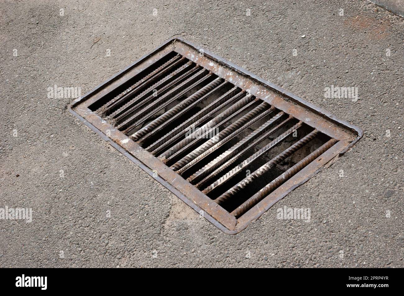 A rusty storm grate in an asphalt road Stock Photo - Alamy