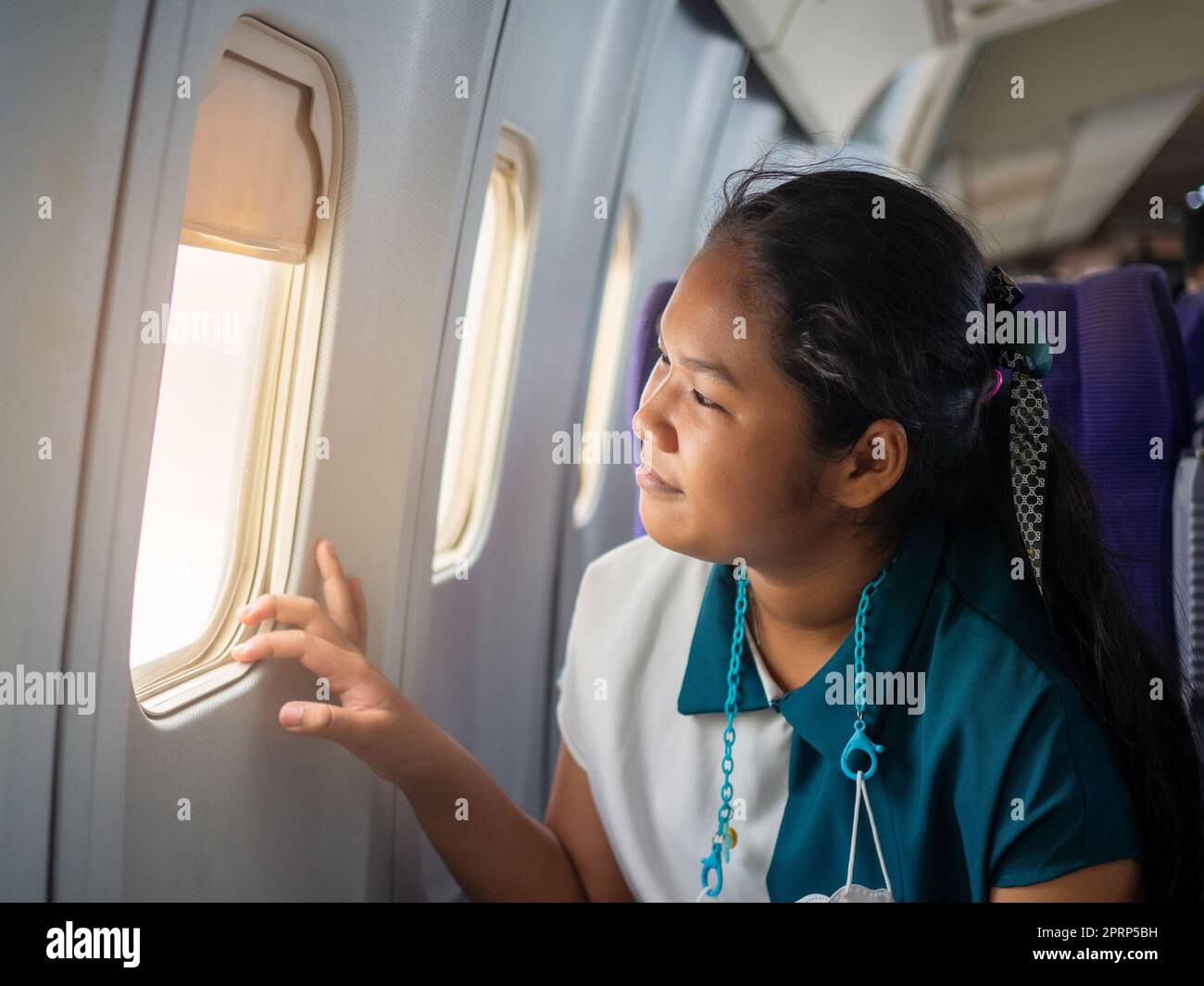 Asian woman sitting looking out of plane window Stock Photo - Alamy