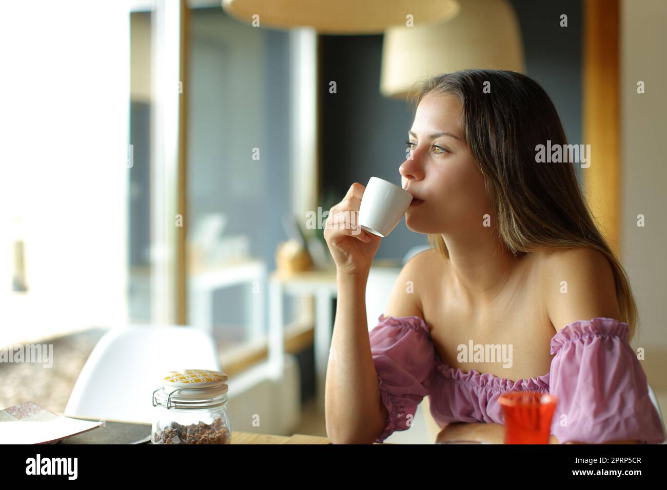Young woman drinking coffee in a restaurant Stock Photo - Alamy