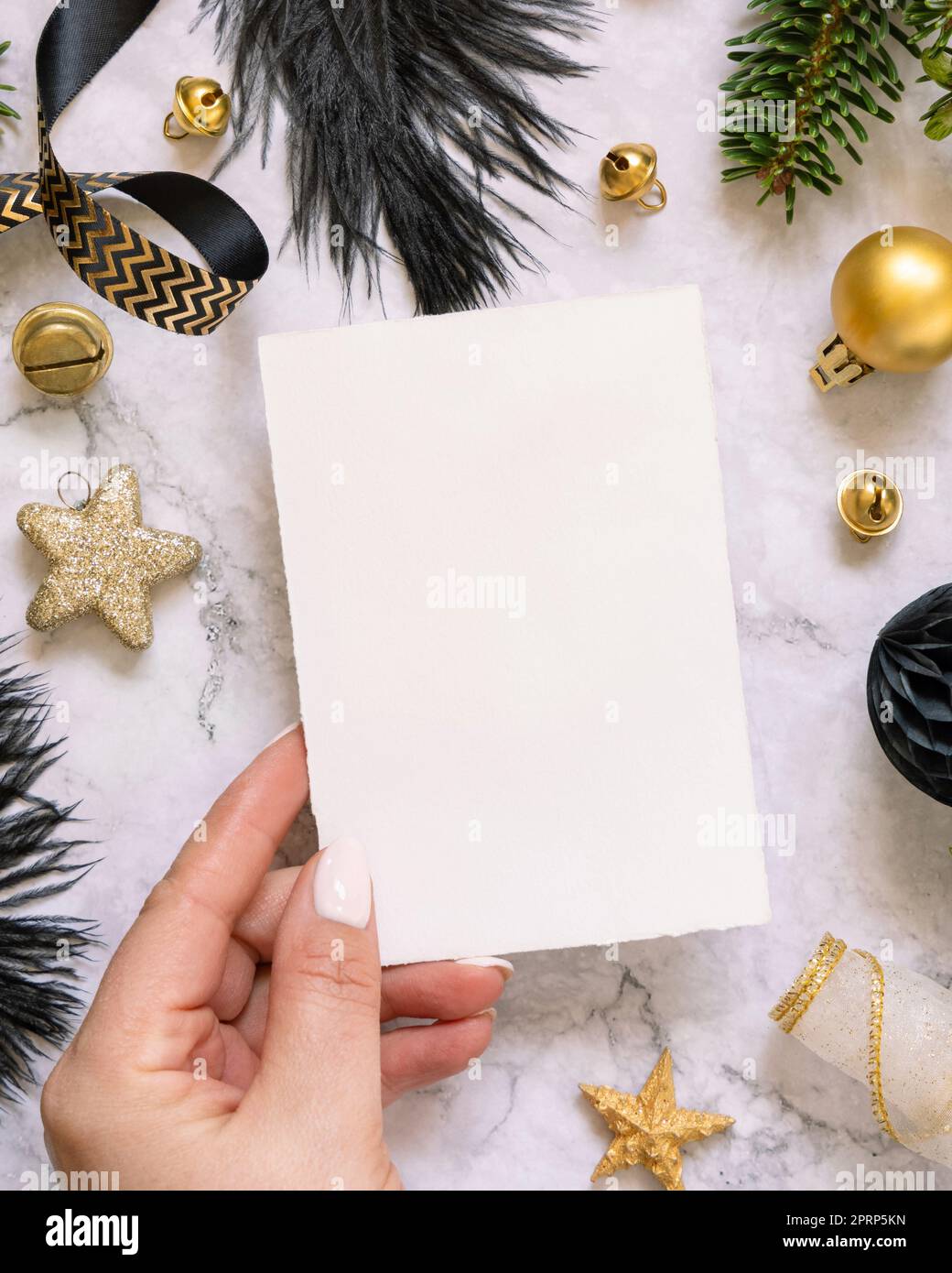 Hand holding Card near black and golden Christmas decorations and fir ...