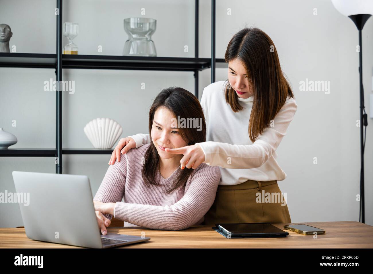 Asian mother and teenage daughter looking at laptop computer at home ...