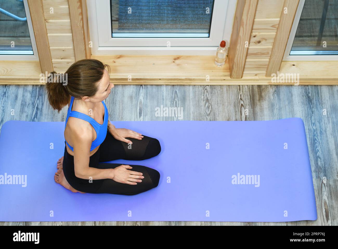 Top view of young woman doing breathing exercises sitting on mat on the ...