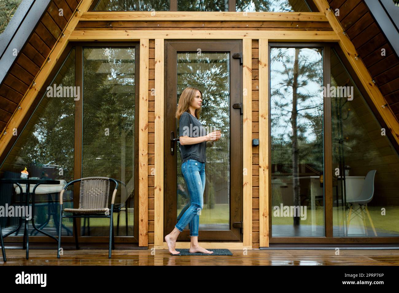 Barefoot woman came out on the wet terrace of a triangular summer house ...