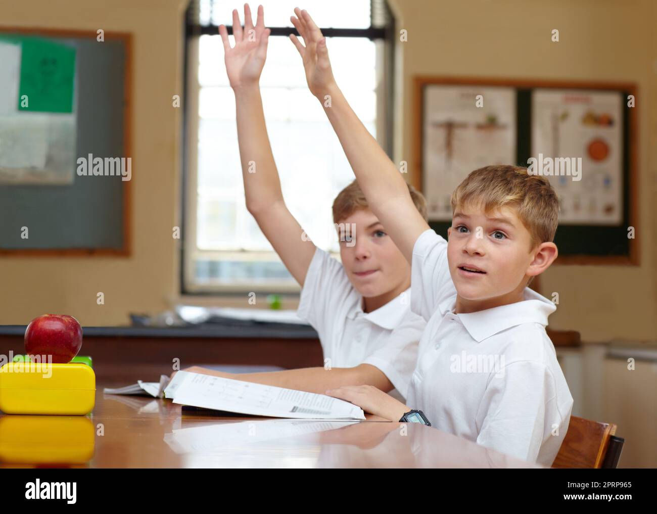 We have the answer. Two young schoolboys raising their hands in a ...