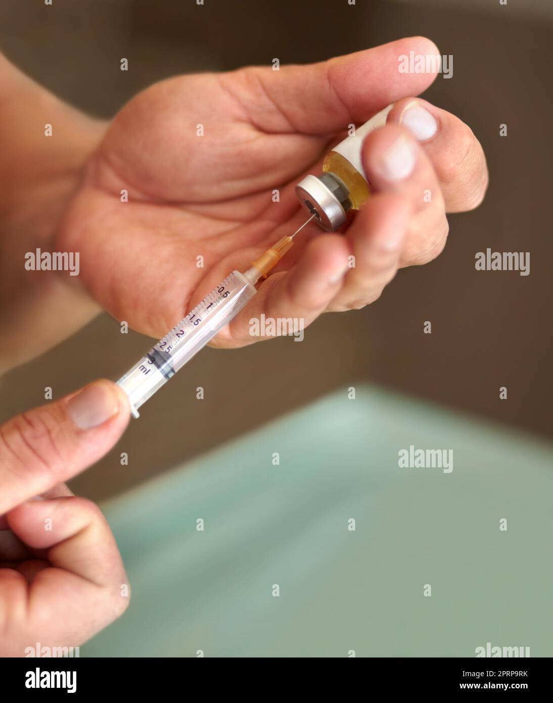 Preparing to inject. Closeup of a man filling a syringe with a clear ...