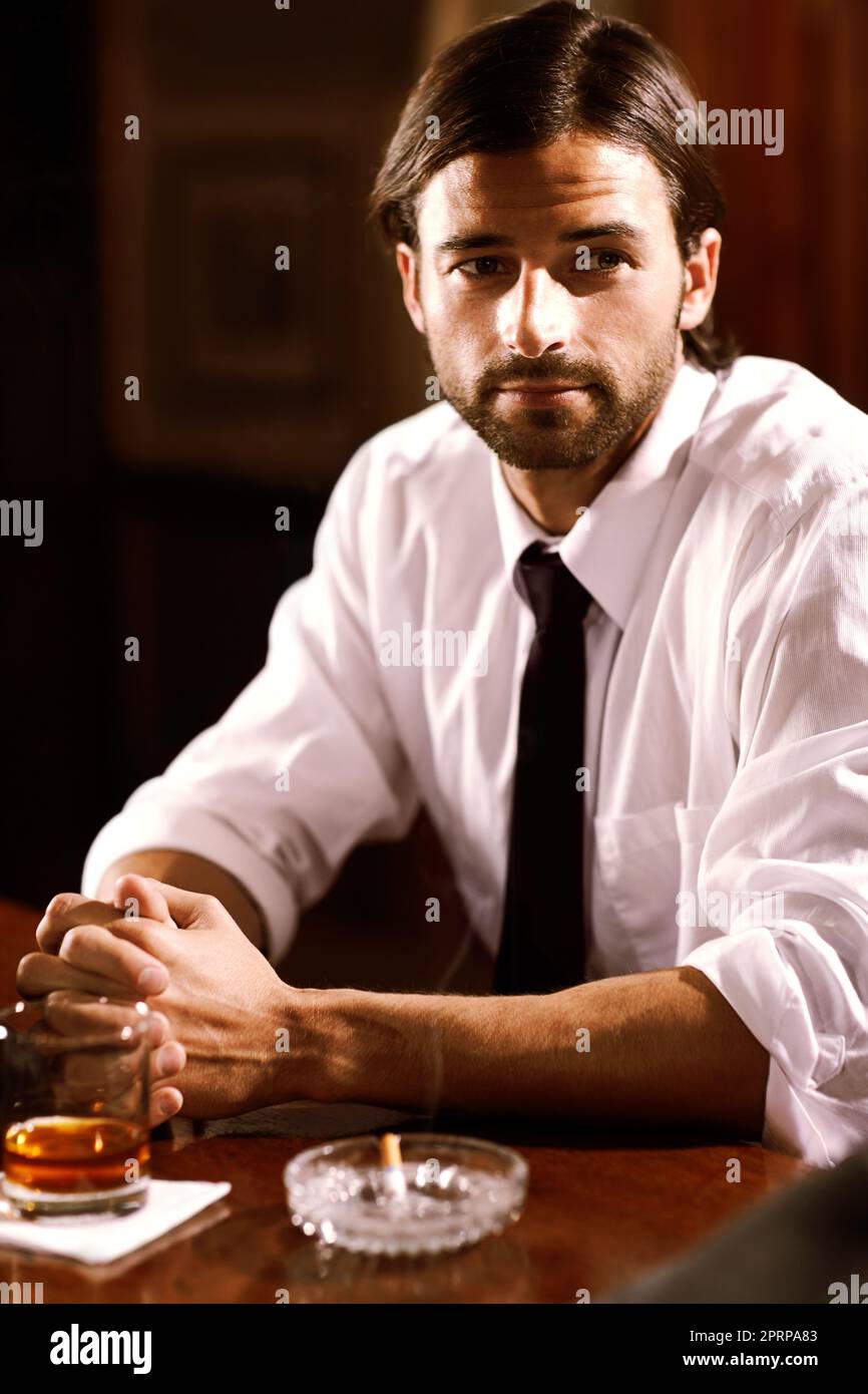 Classy club clientele. A well-dressed young man sitting at a bar with a ...