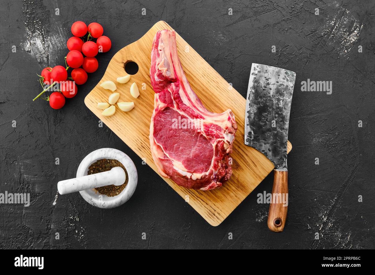 Top view of beef ribeye steak bone-in with spice on black background ...
