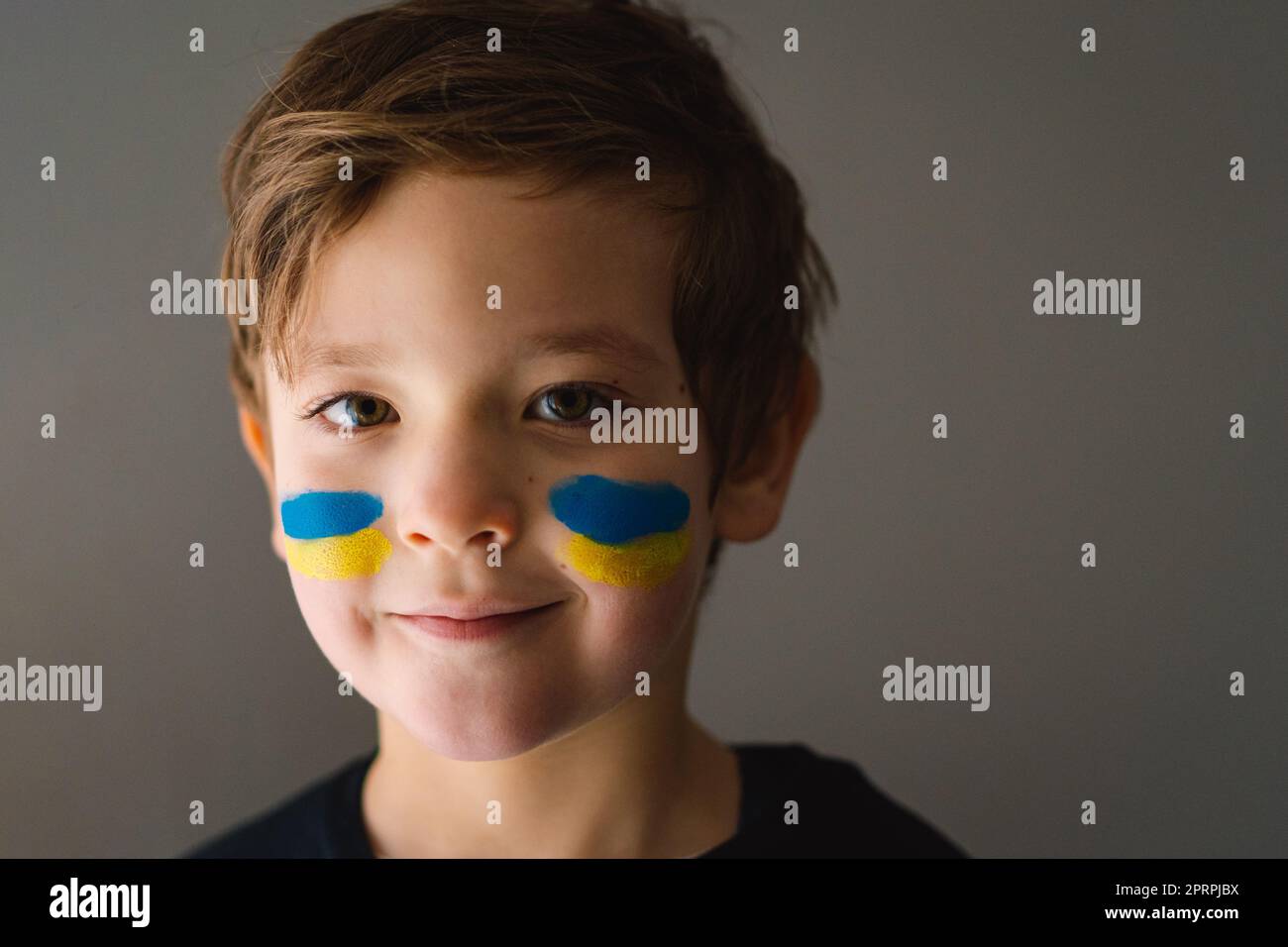 Portrait of a Ukrainian boy with a face painted with the colors of the ...