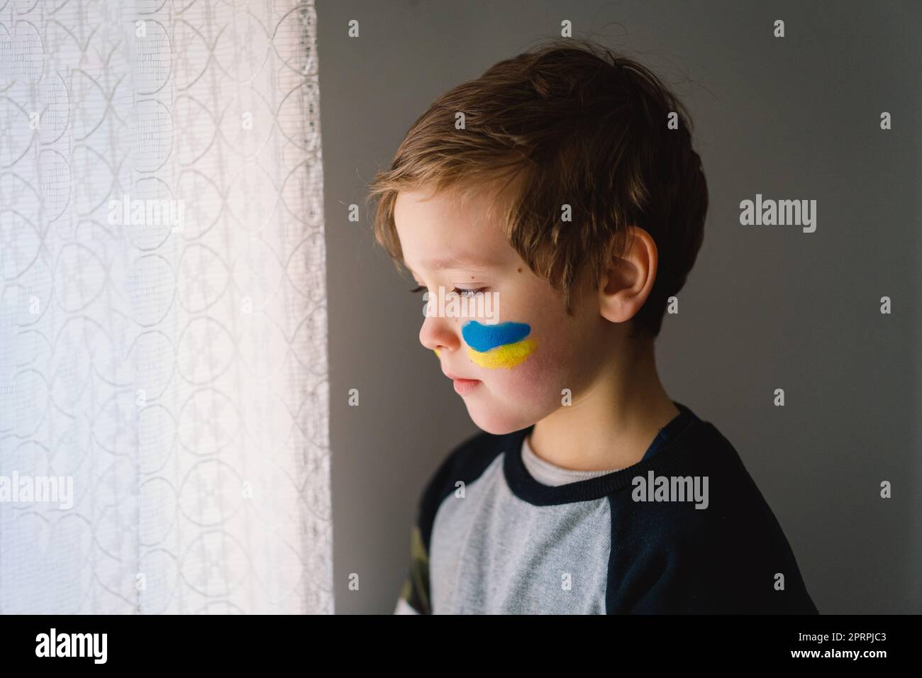 Portrait of a Ukrainian boy with a face painted with the colors of the ...
