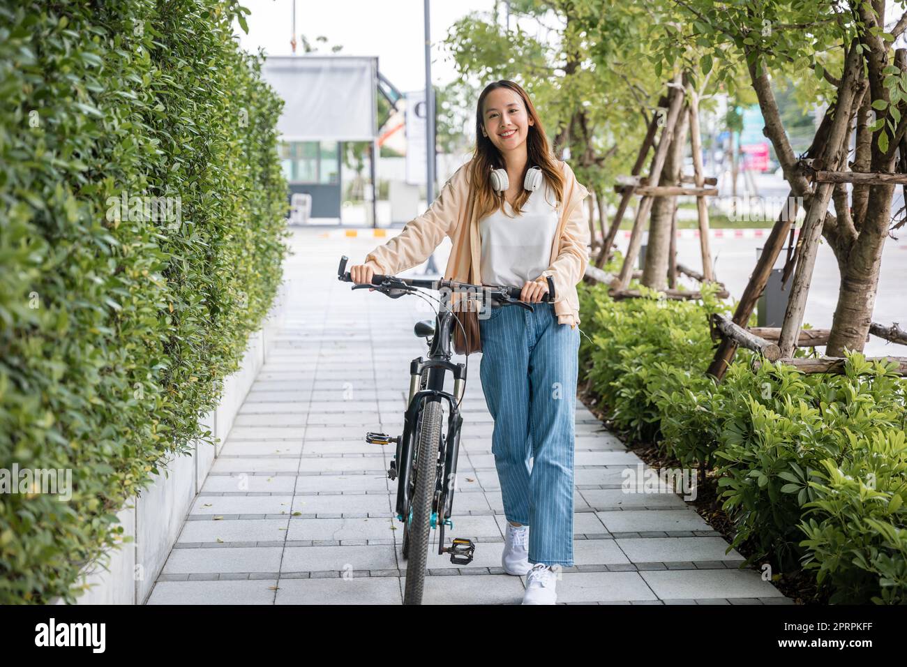 Happy female smiling walk down the street with her bike on city road ...
