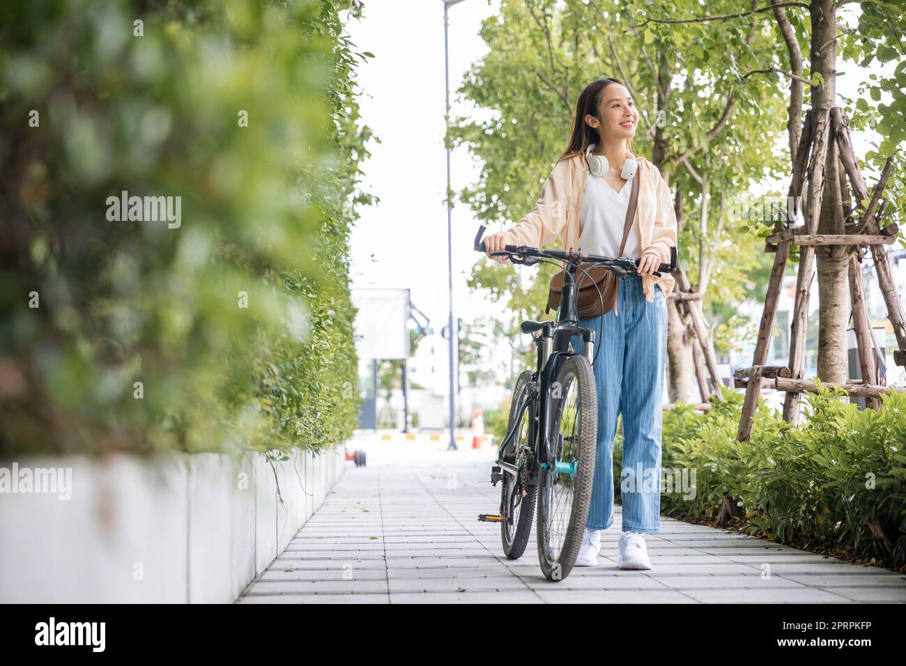 Happy female smiling walk down the street with her bike on city road ...