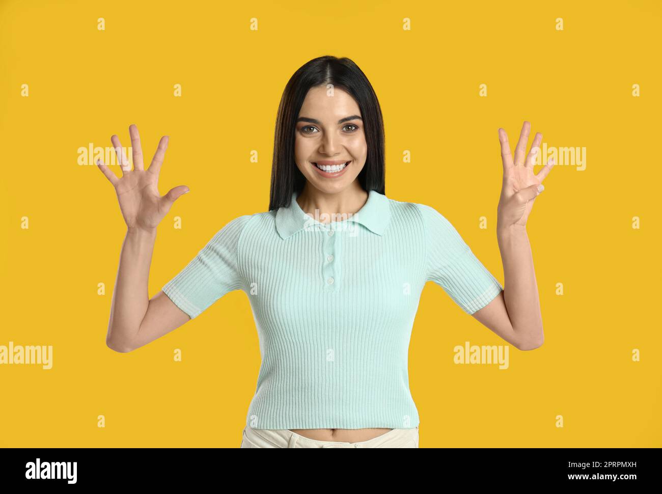 Woman showing number nine with her hands on yellow background Stock ...