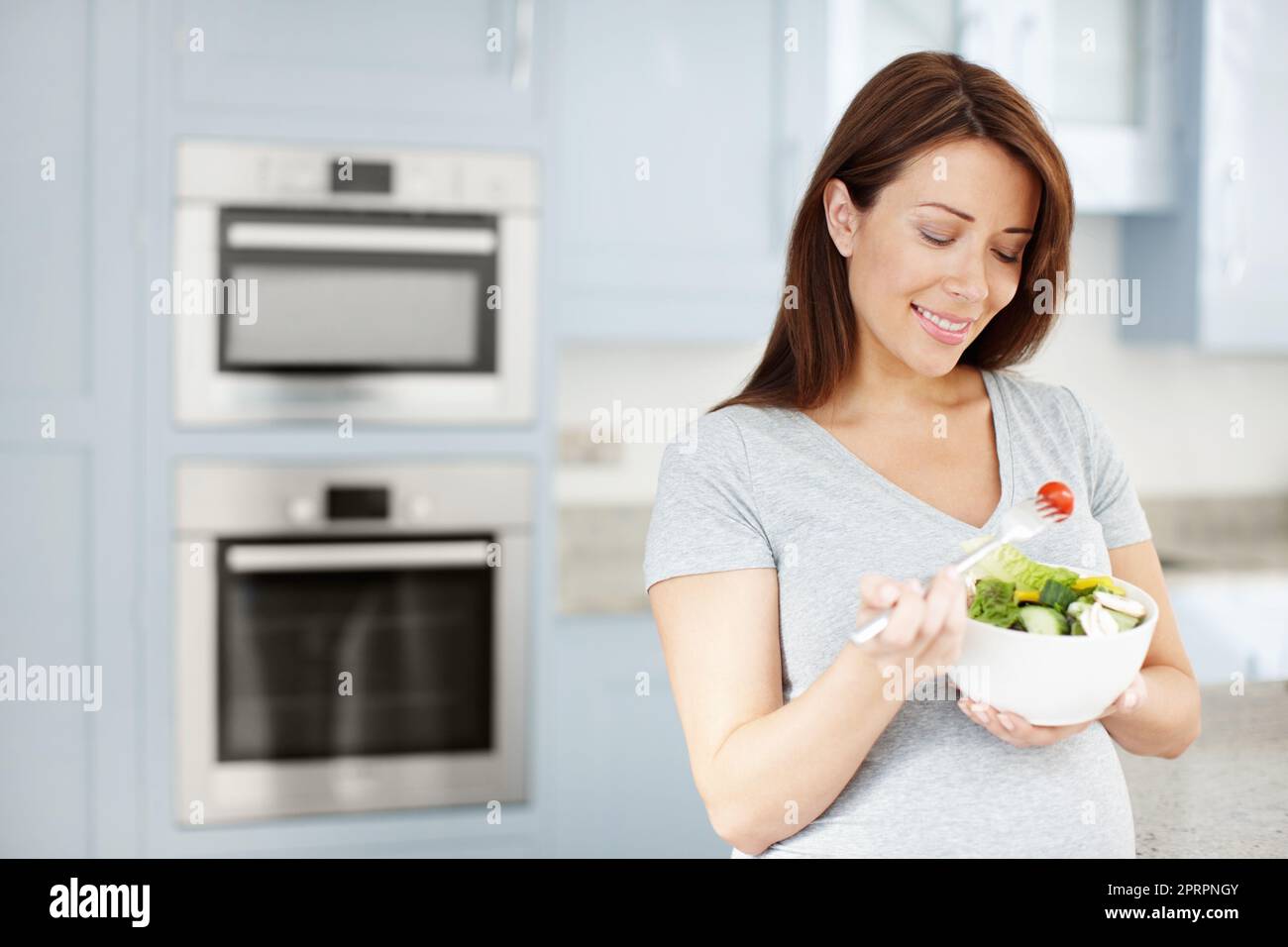 Eating for two - Healthy Diet. A pregnant woman eating a healthy salad ...