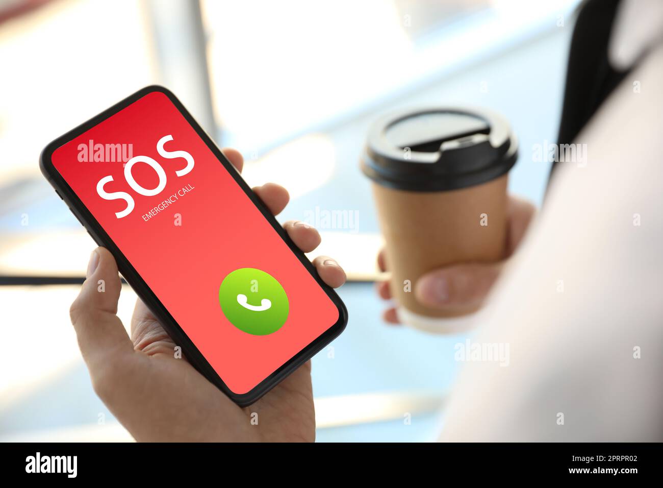Man holding smartphone with emergency call SOS on screen indoors ...