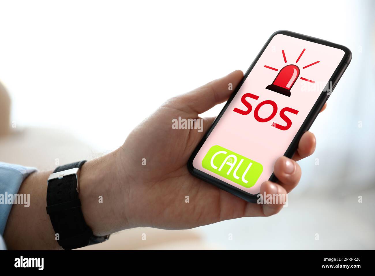 Man holding smartphone with emergency call SOS on screen indoors ...
