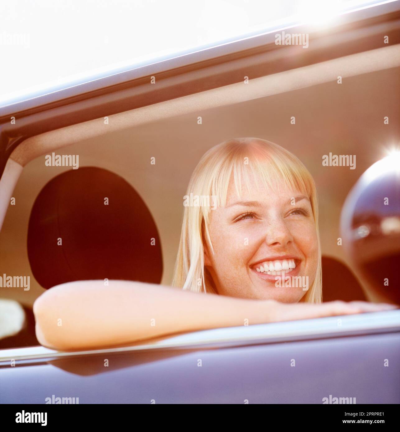 Blond female in a car looking away with a smile. Smiling blond female ...