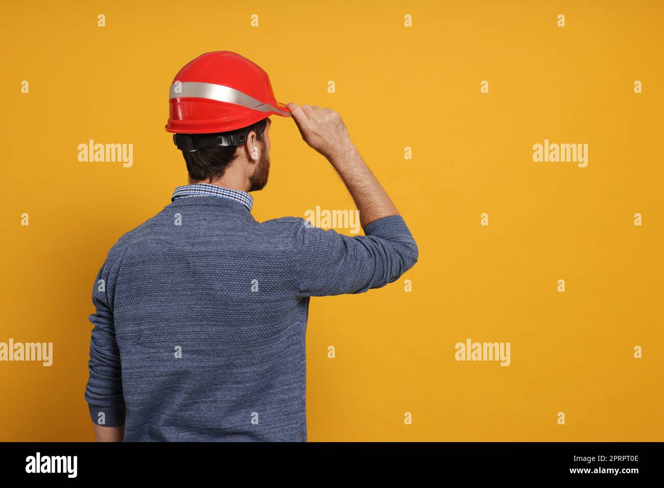 Professional engineer in hard hat on yellow background, back view ...