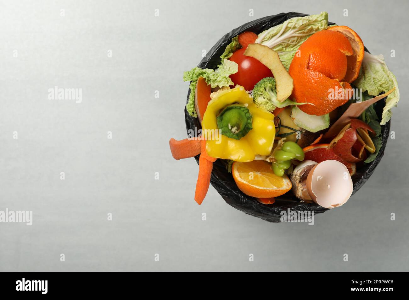 Natural garbage in trash bin on light background, top view with space ...