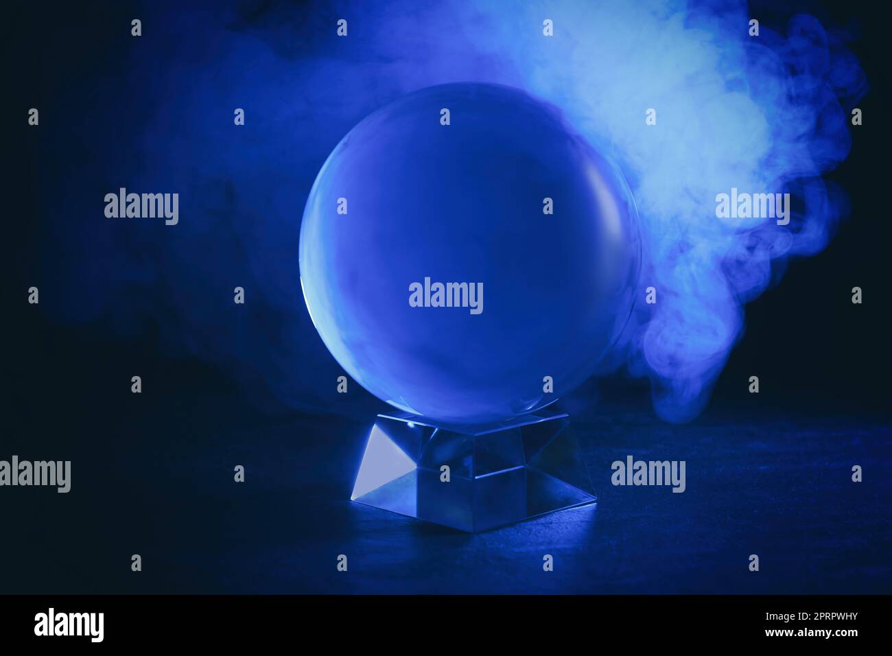Magic crystal ball on table and smoke against dark background. Making ...