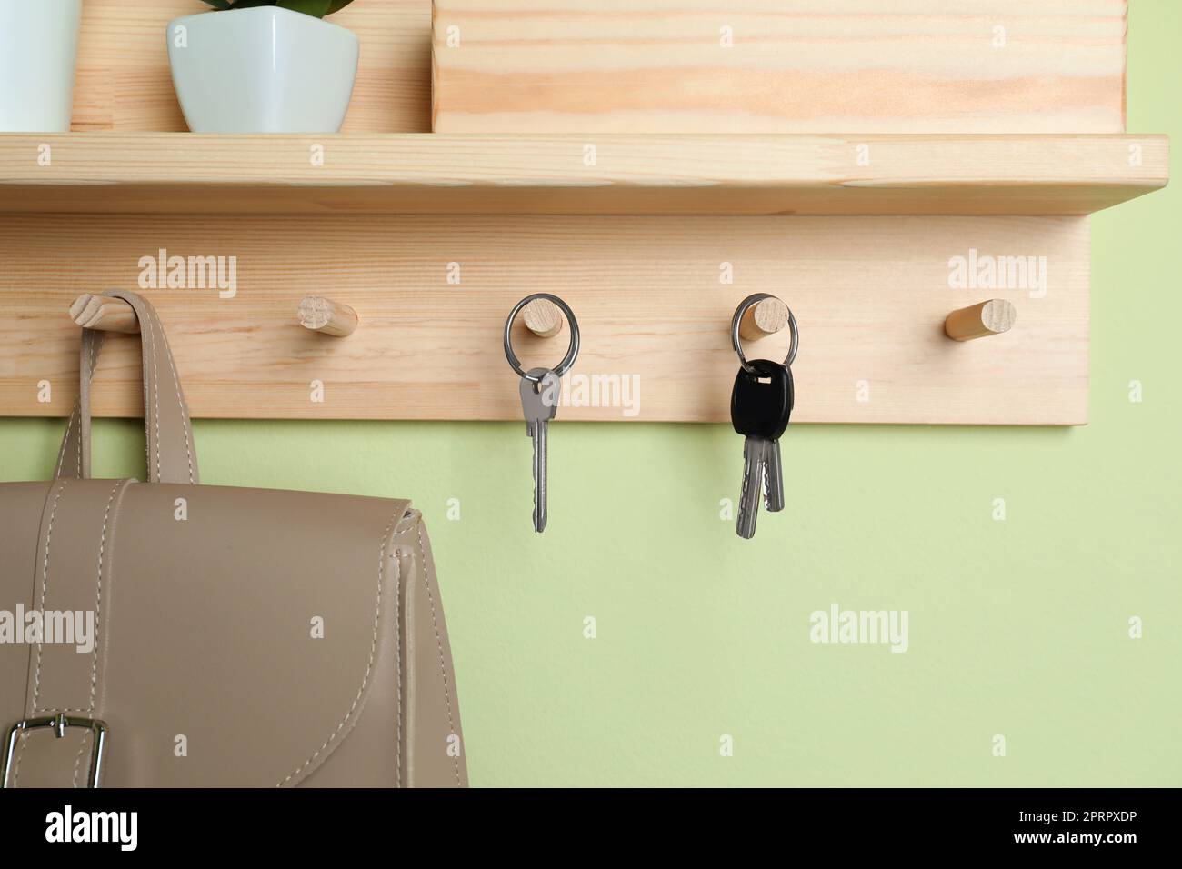 Wooden hanger for keys on light green wall Stock Photo - Alamy