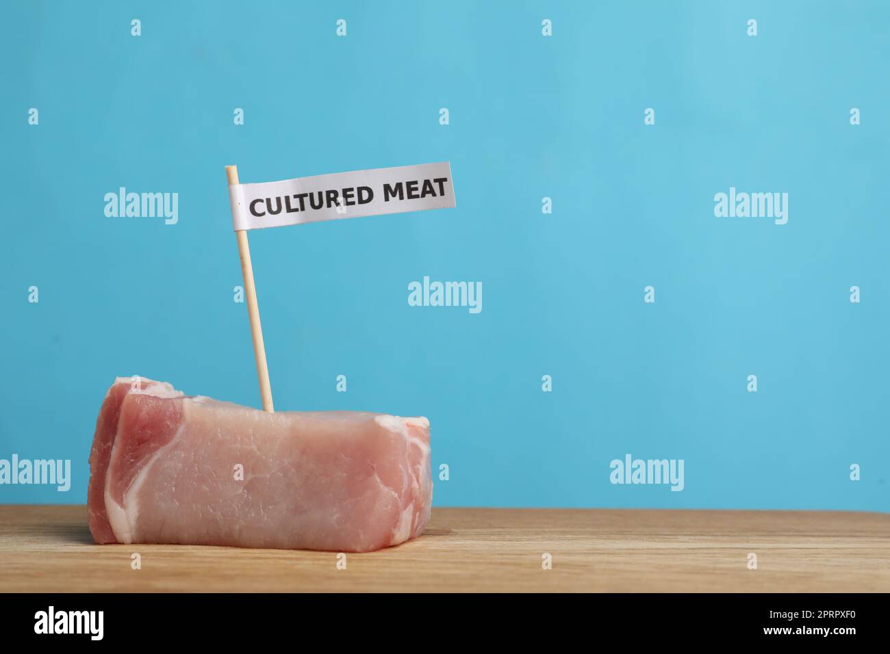 Sample of lab grown pork labeled Cultured Meat on wooden table. Space ...