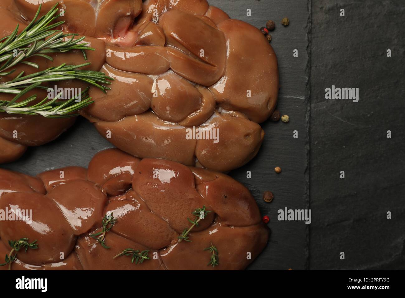 Fresh raw kidneys with rosemary and thyme on black table, top view ...