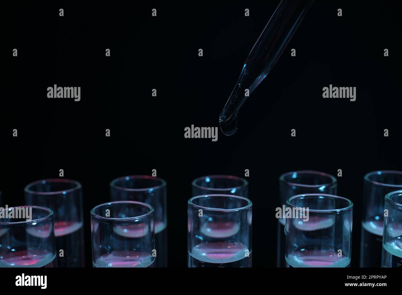 Dripping reagent into test tube on black background, closeup ...