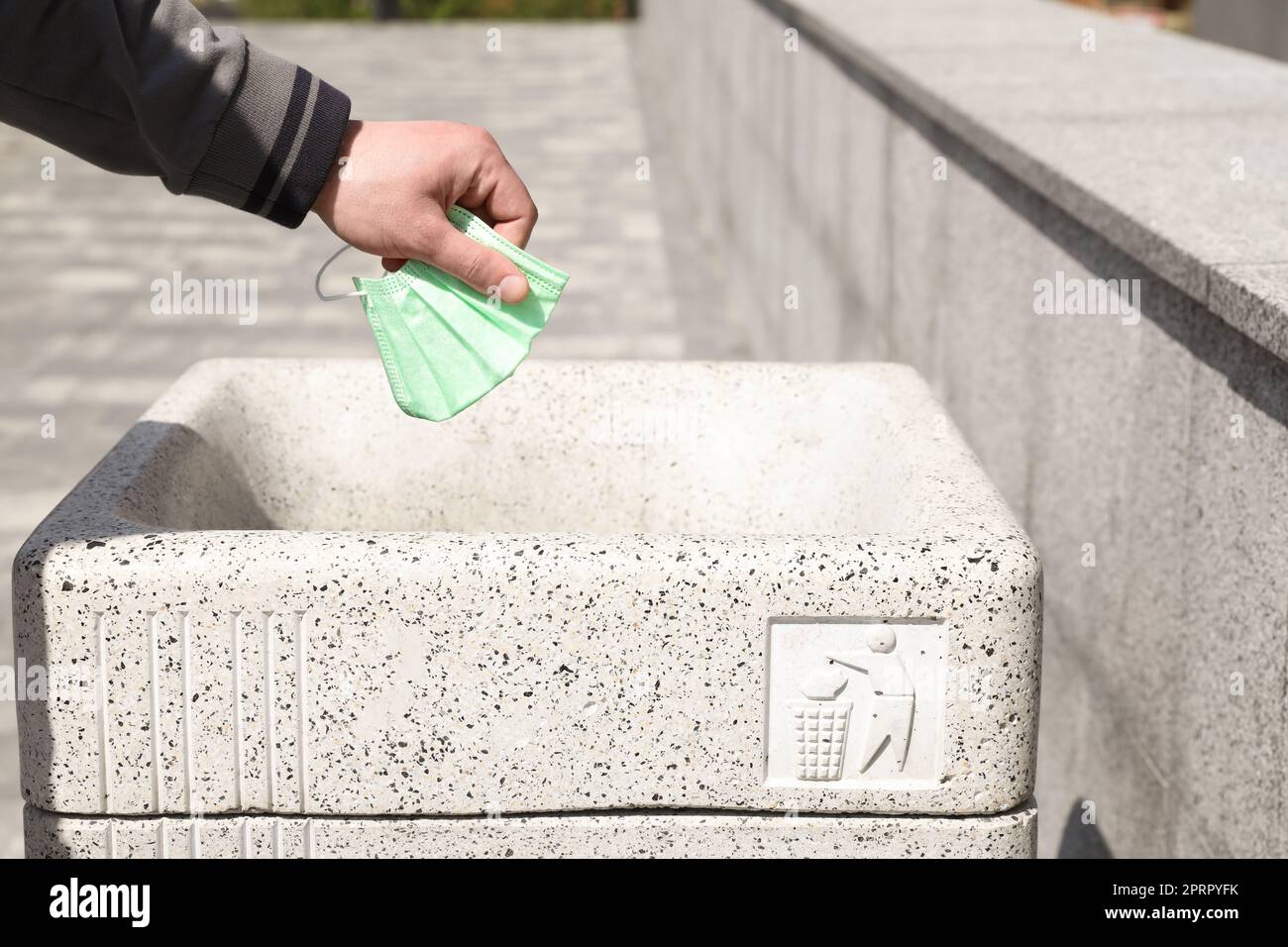 Man throwing medical mask into trash bin outdoors, closeup Stock Photo ...