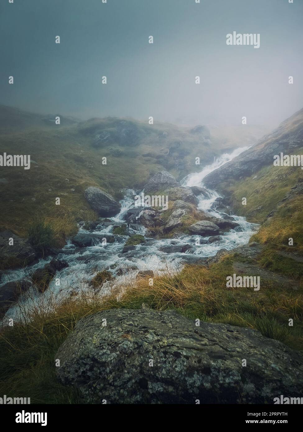 Mountain stream flowing fast across a rocky valley in Fagaras Mountains ...