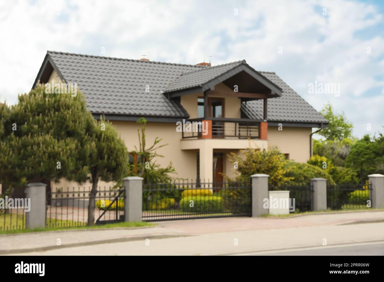 View of suburban street with beautiful house behind fence Stock Photo ...