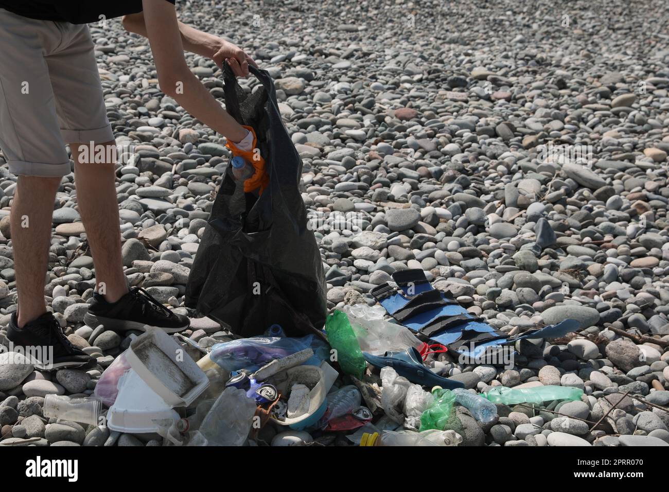 Man with trash bag collecting garbage in nature, closeup. Environmental ...