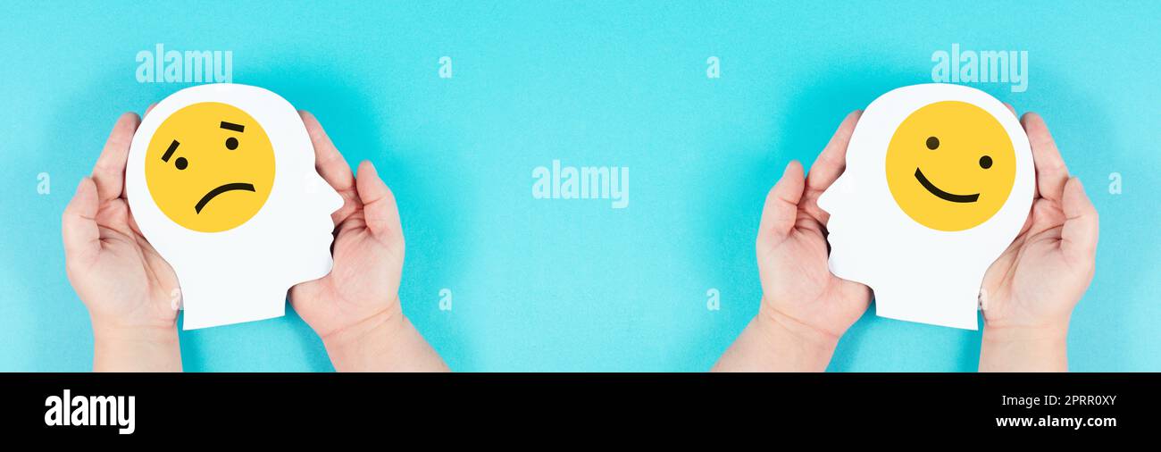 Holding a head with a sad and a happy face in the hands, mental health ...