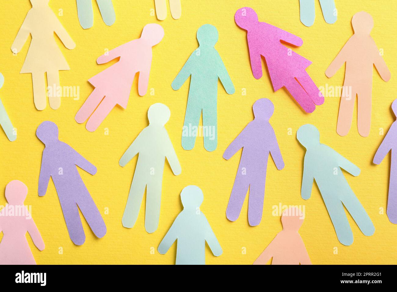 Many different paper human figures on yellow background, flat lay ...