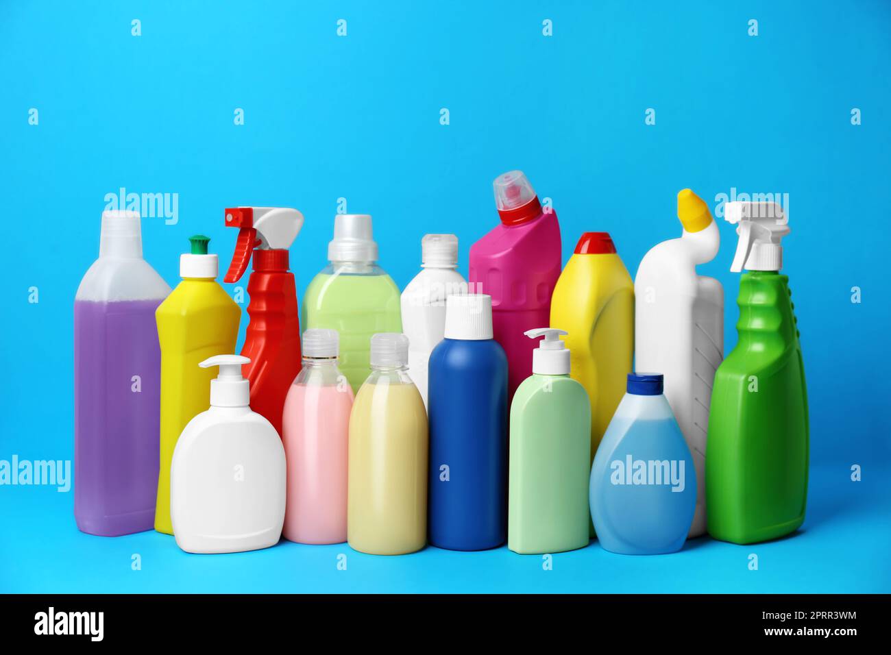 Many bottles of different detergents on light blue background. Cleaning ...