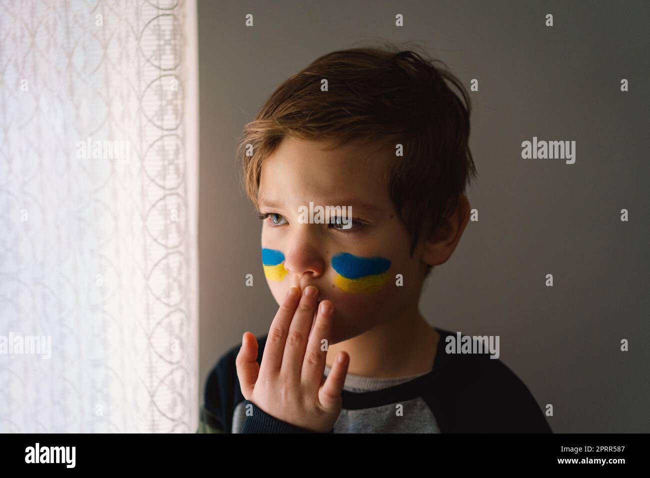 Portrait of a Ukrainian boy with a face painted with the colors of the ...